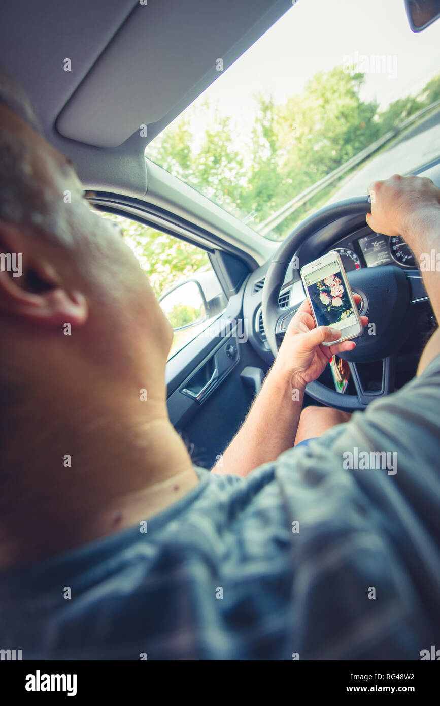 A man in the front seat of his car is photographing the road in front ...