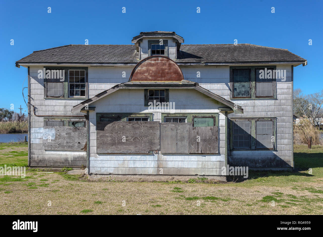 Front view of abandoned and derelict building with patchy green grass ...