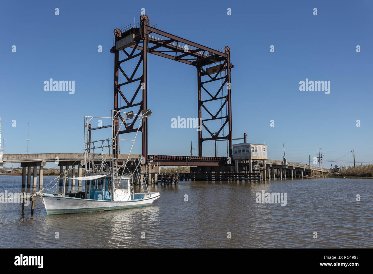 Vertical lift bridge over river with fishing boat tied to shore with ...
