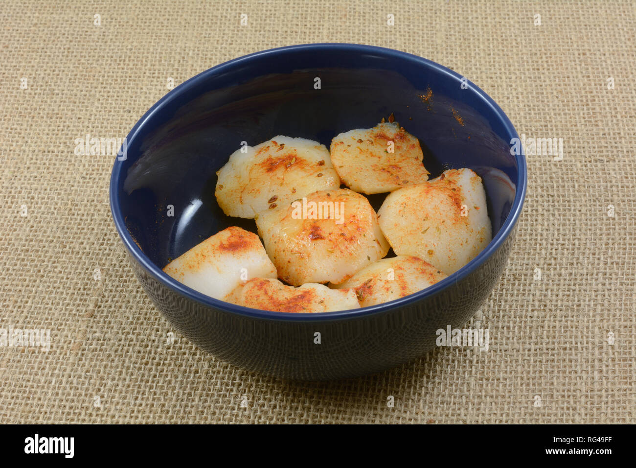 Cajun seasoned fresh raw sea scallops seafood shellfish in blue bowl ...