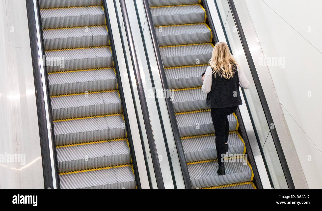 Woman going up escalator hi-res stock photography and images - Alamy