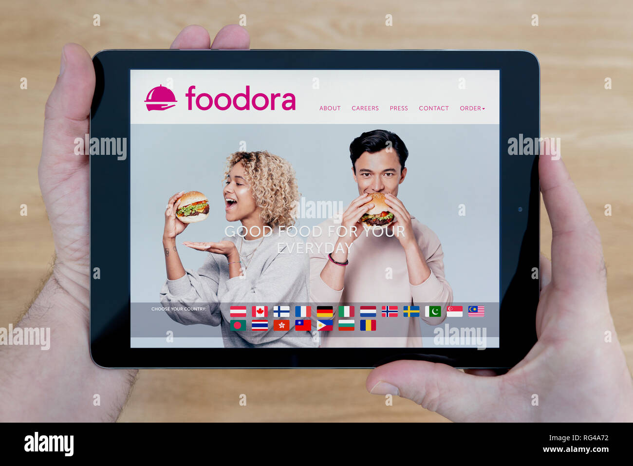A man looks at the Foodora website on his iPad tablet device, shot ...