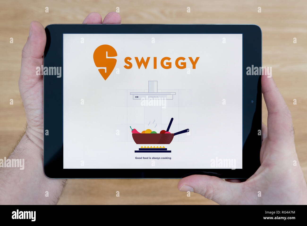 A man looks at the Swiggy website on his iPad tablet device, shot ...