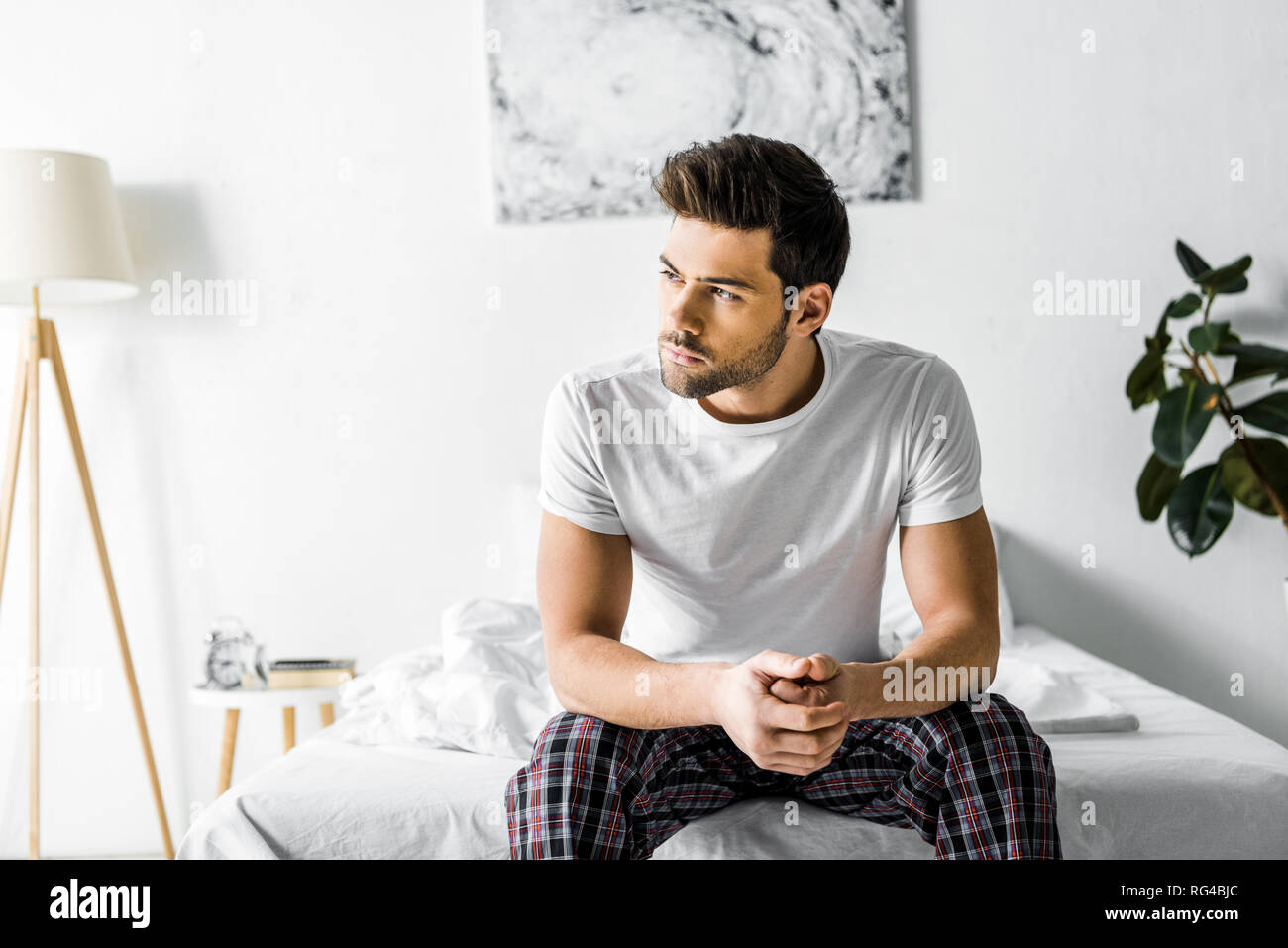 handsome thoughtful man in pajamas sitting on bed in the morning Stock ...