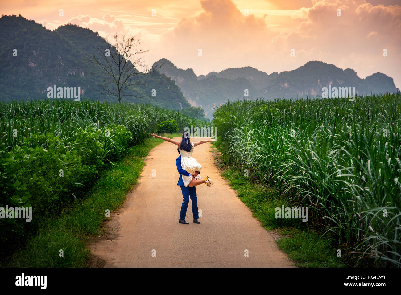 Happy couple having fun in a sugar cane field at sunset Stock Photo - Alamy