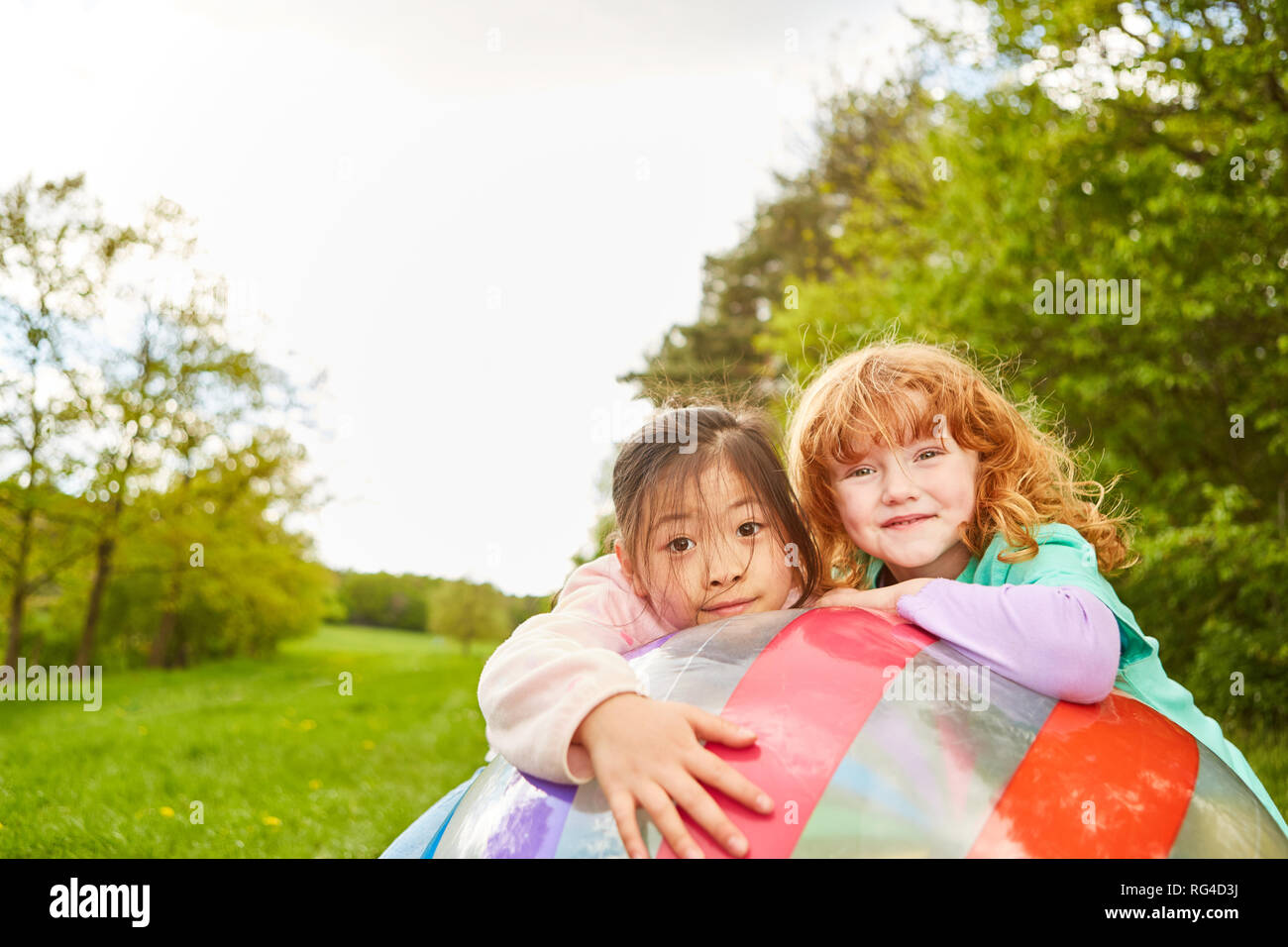 Two girls as best girlfriends playing ball together in the park in ...