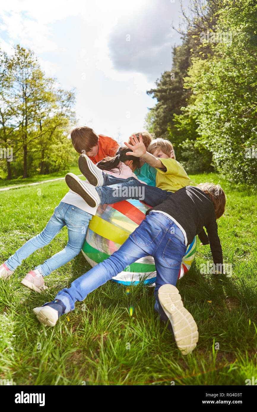 Group of kids is raging with a colorful ball around in the park in the ...