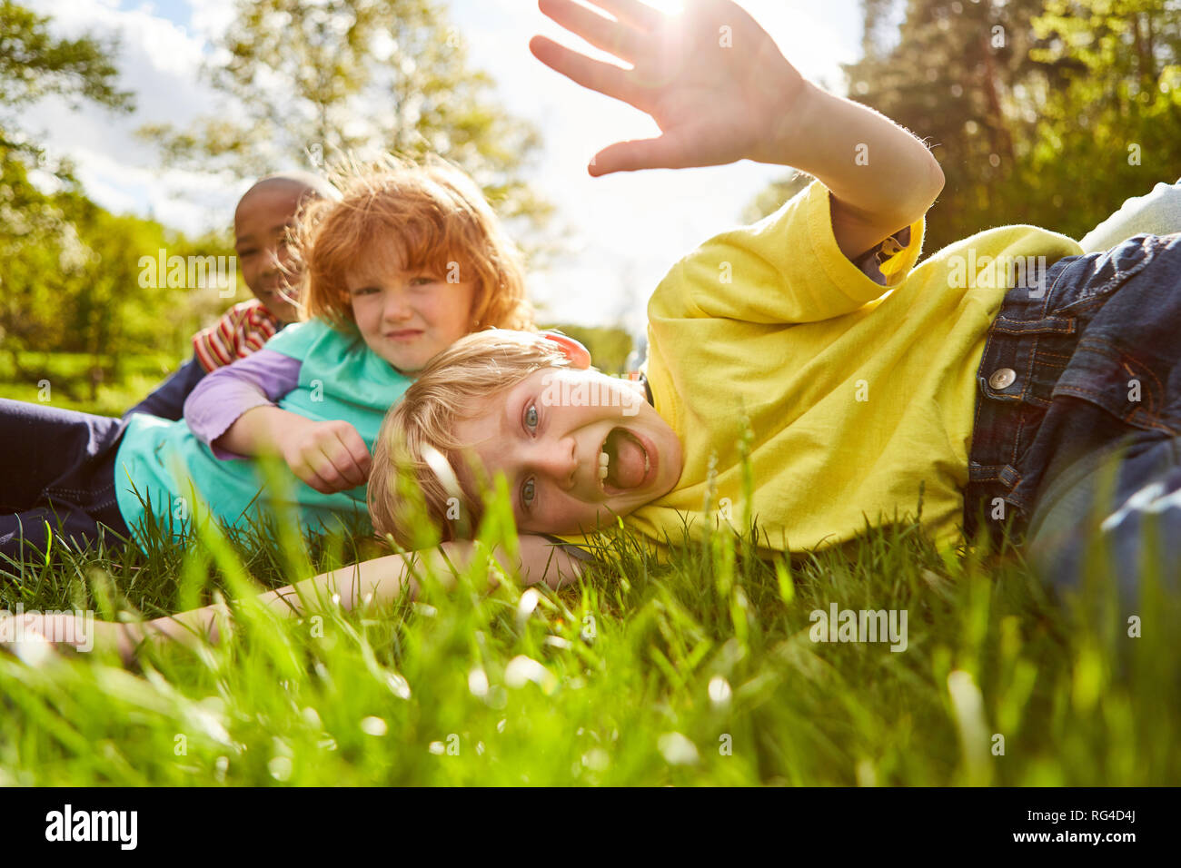 Children playing as friends and silly around on a meadow in the summer ...