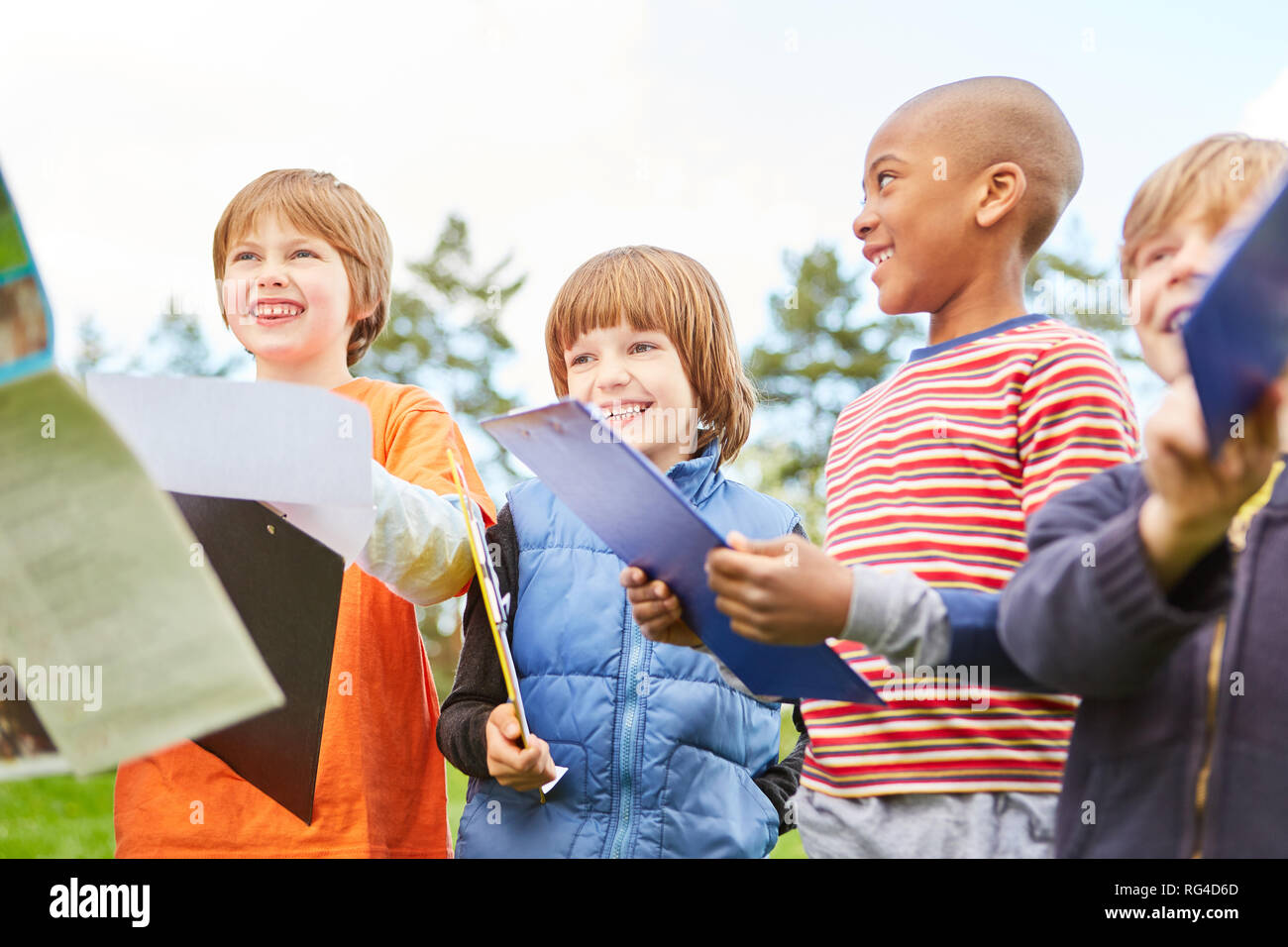 Happy children on a treasure hunt as a scavenger hunt in nature with ...