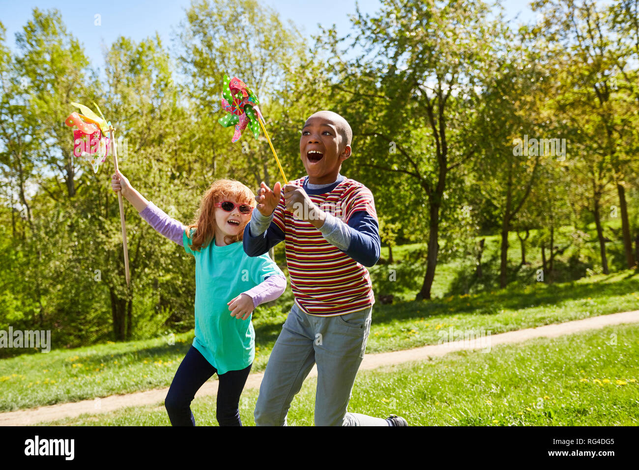 Boy and girl on a meadow with colorful wind wheels celebrates kids ...