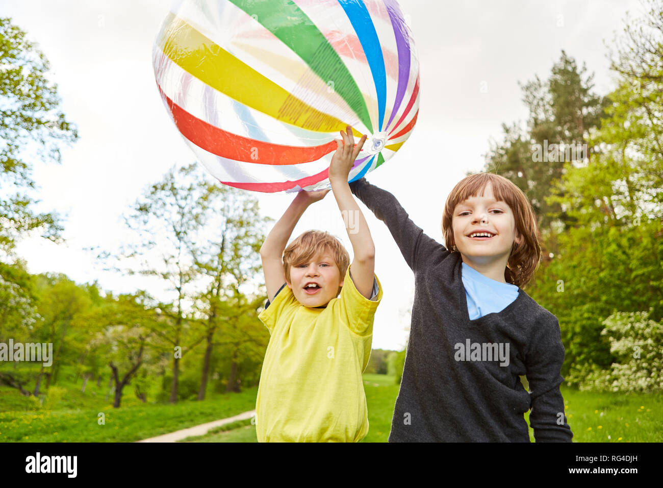 Two children smile and proudly hold a colorful ball as the winner in ...