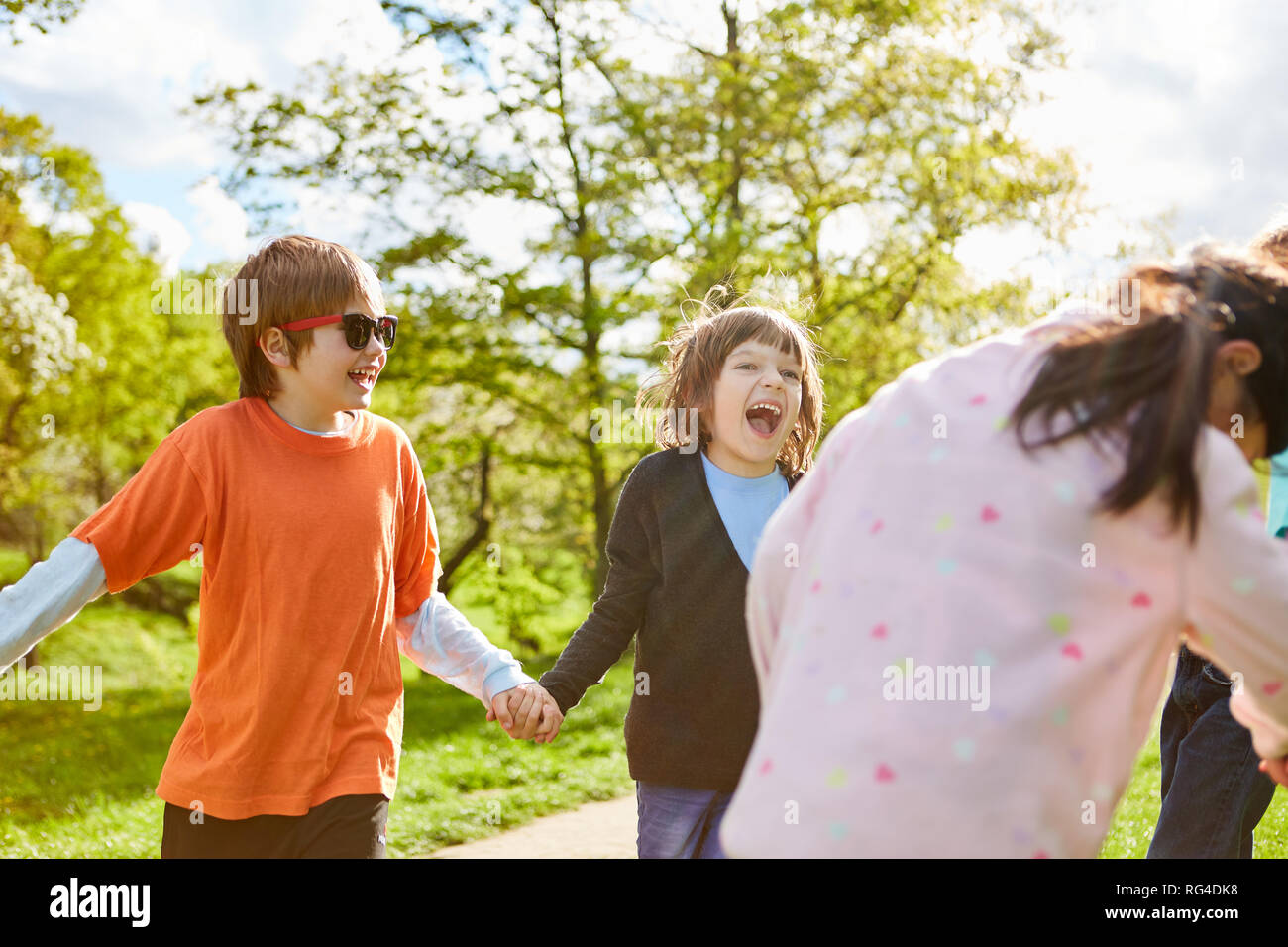 Group of kids has fun on a kids birthday and dancing in circle around ...