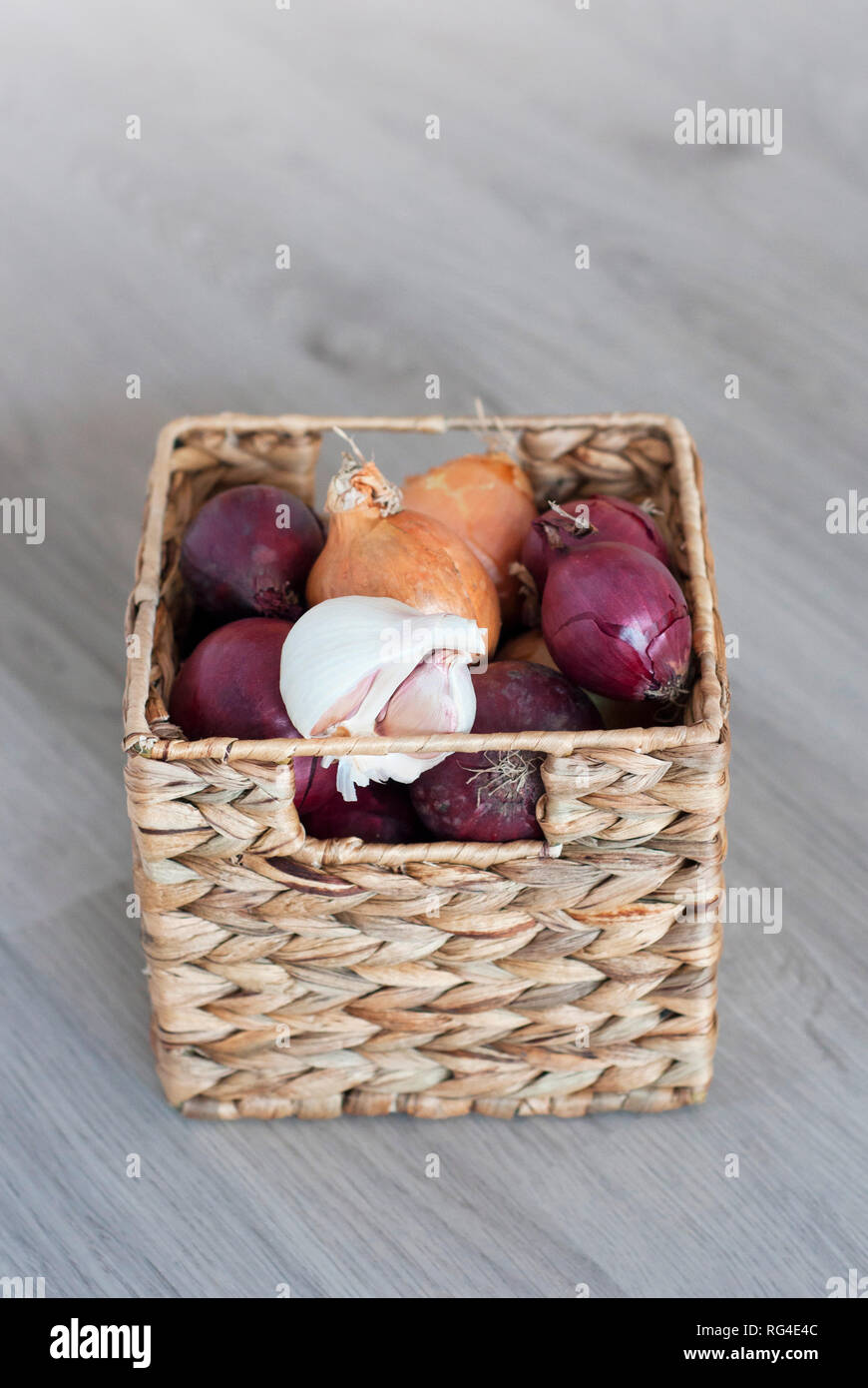 Purple and white onions in squar, wicker box isolated on the wooden ...