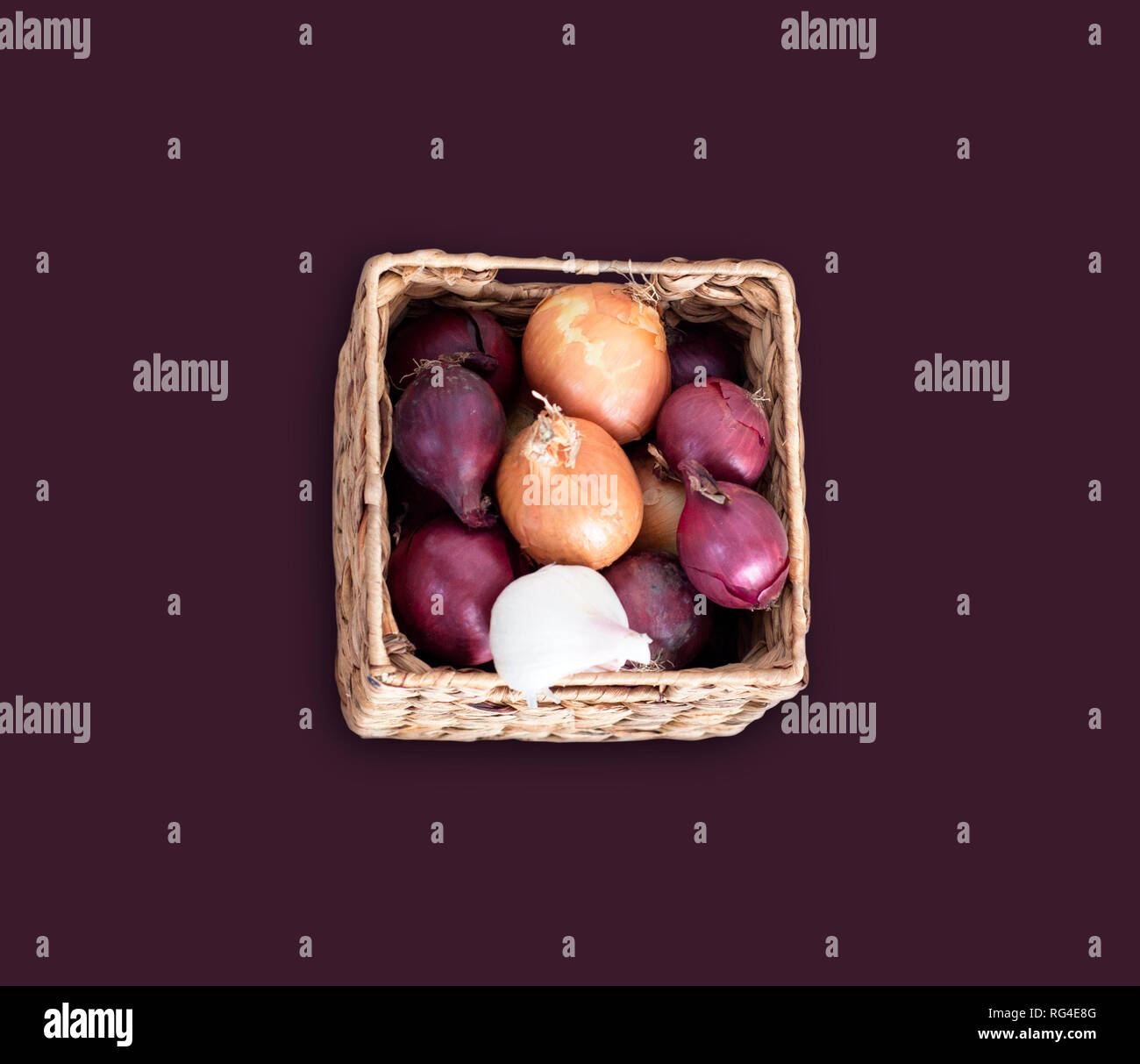Purple and white onions in squar, wicker box isolated on bordeaux ...