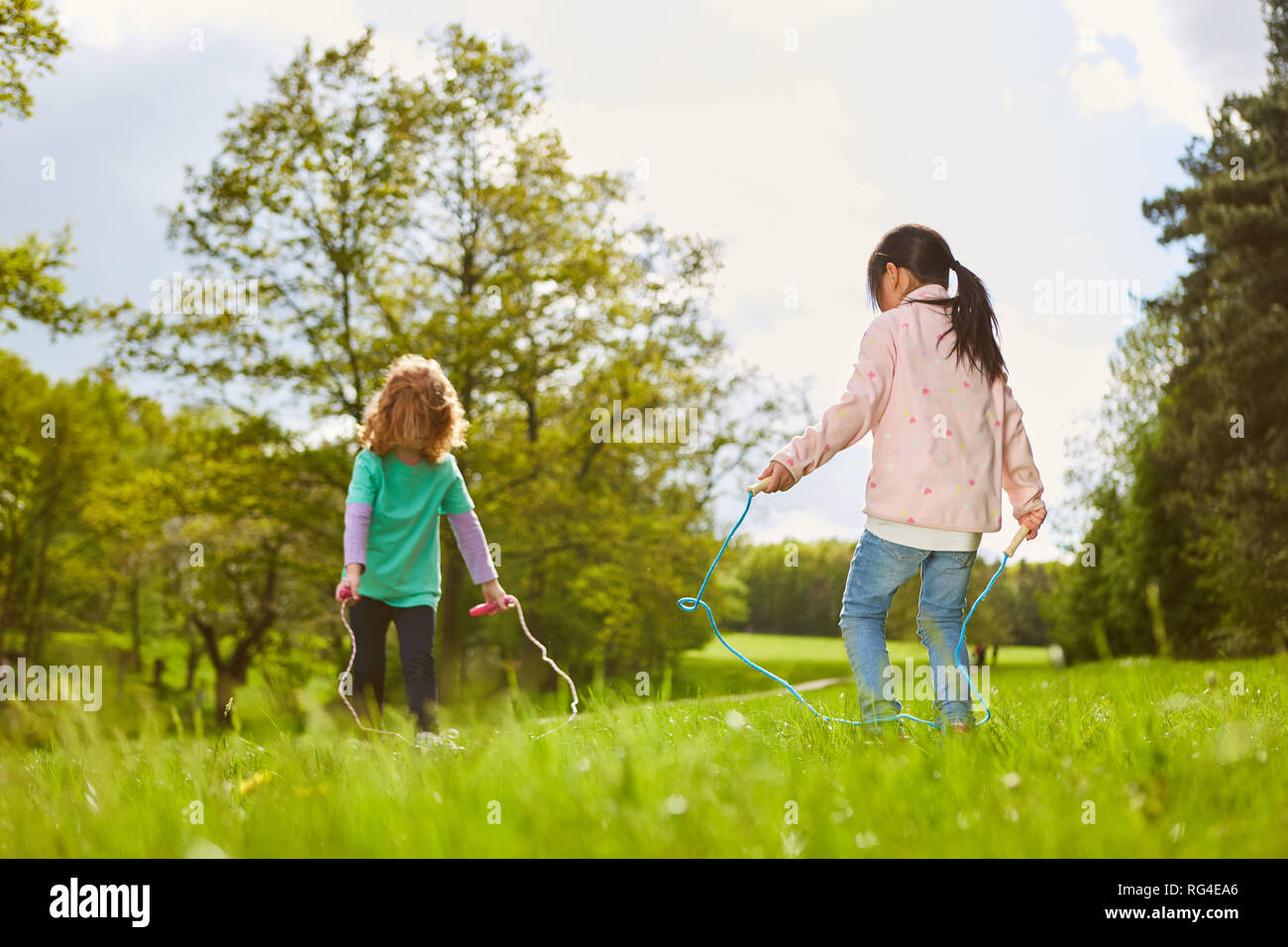 Two girls together while jumping rope in kindergarten on a meadow in ...