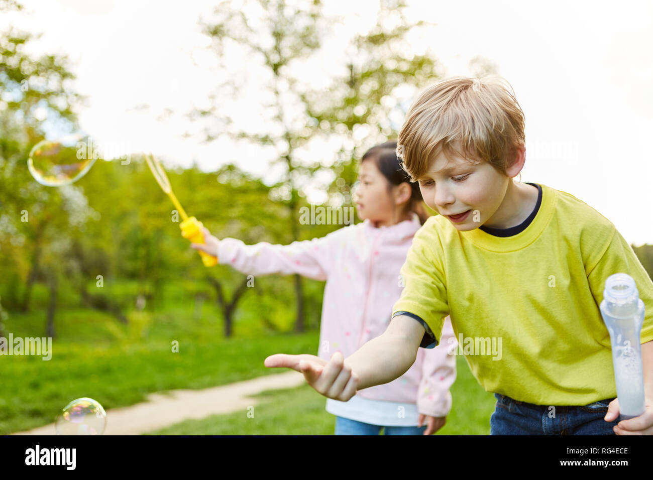 Two children are making soap bubbles together in the park in ...