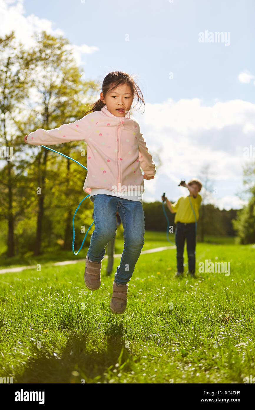 Girl has fun in rope jumping in the summer in the park on vacation with ...