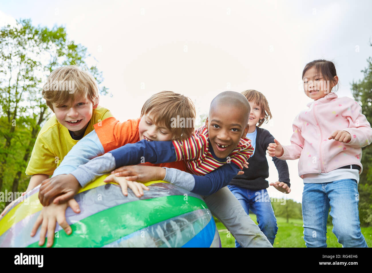 Multicultural kids group has fun playing ball in the park in ...