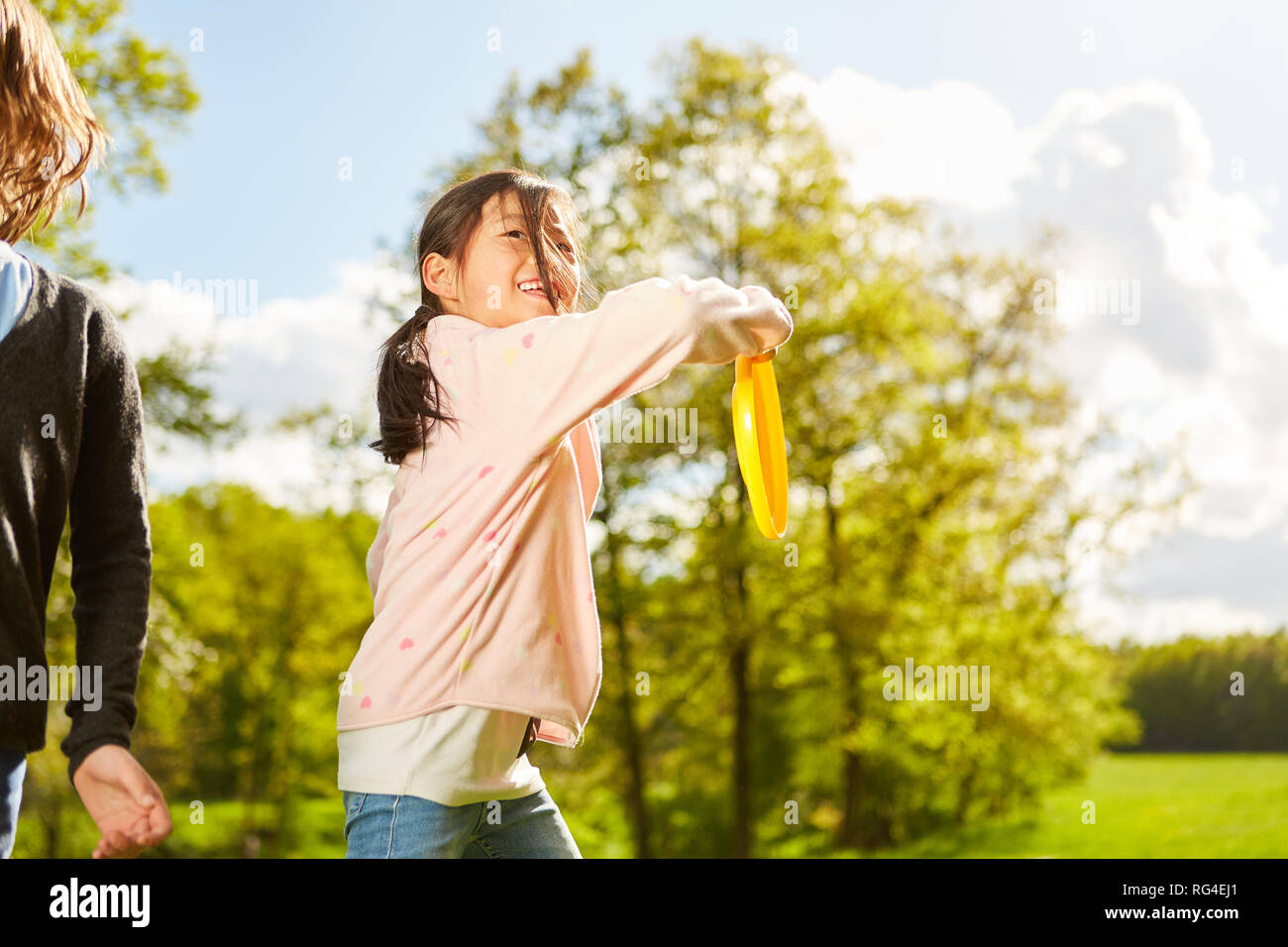 Girl in the summer in the park has fun playing frisbee with her friends ...