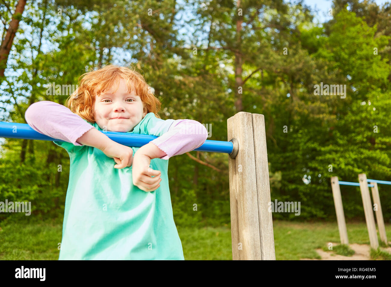 Little girl is playing at a climbing frame on a playground in summer ...