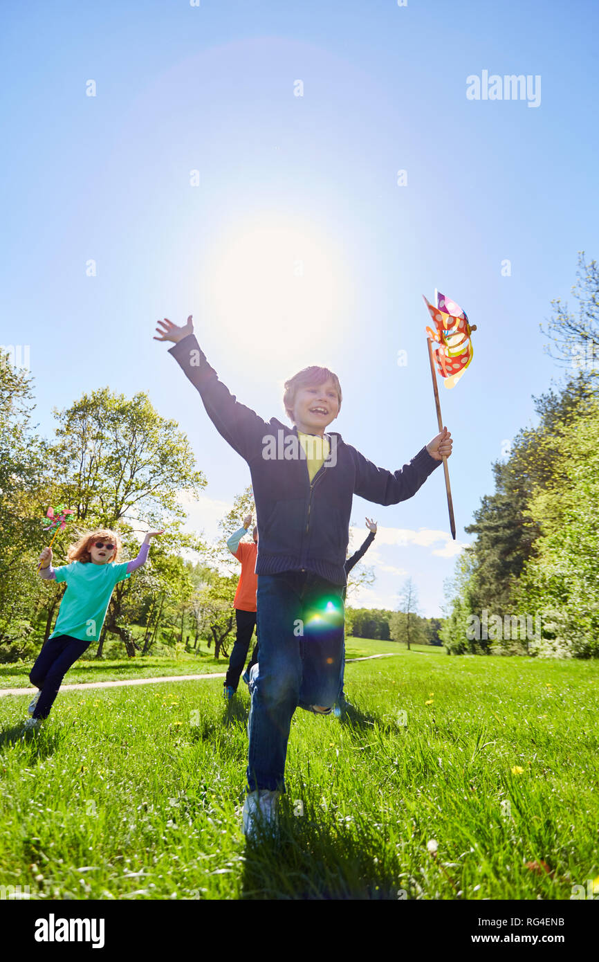 Cheerful children are running in the sunshine with wind turbines as a ...
