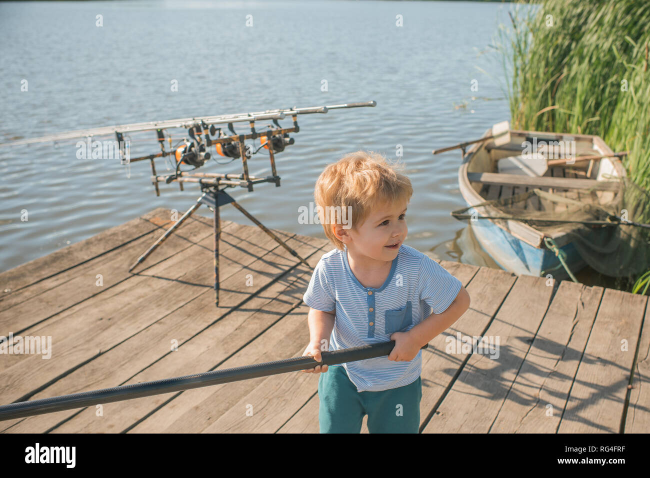 Fisher boy with fishing rod on wooden pier Stock Photo - Alamy