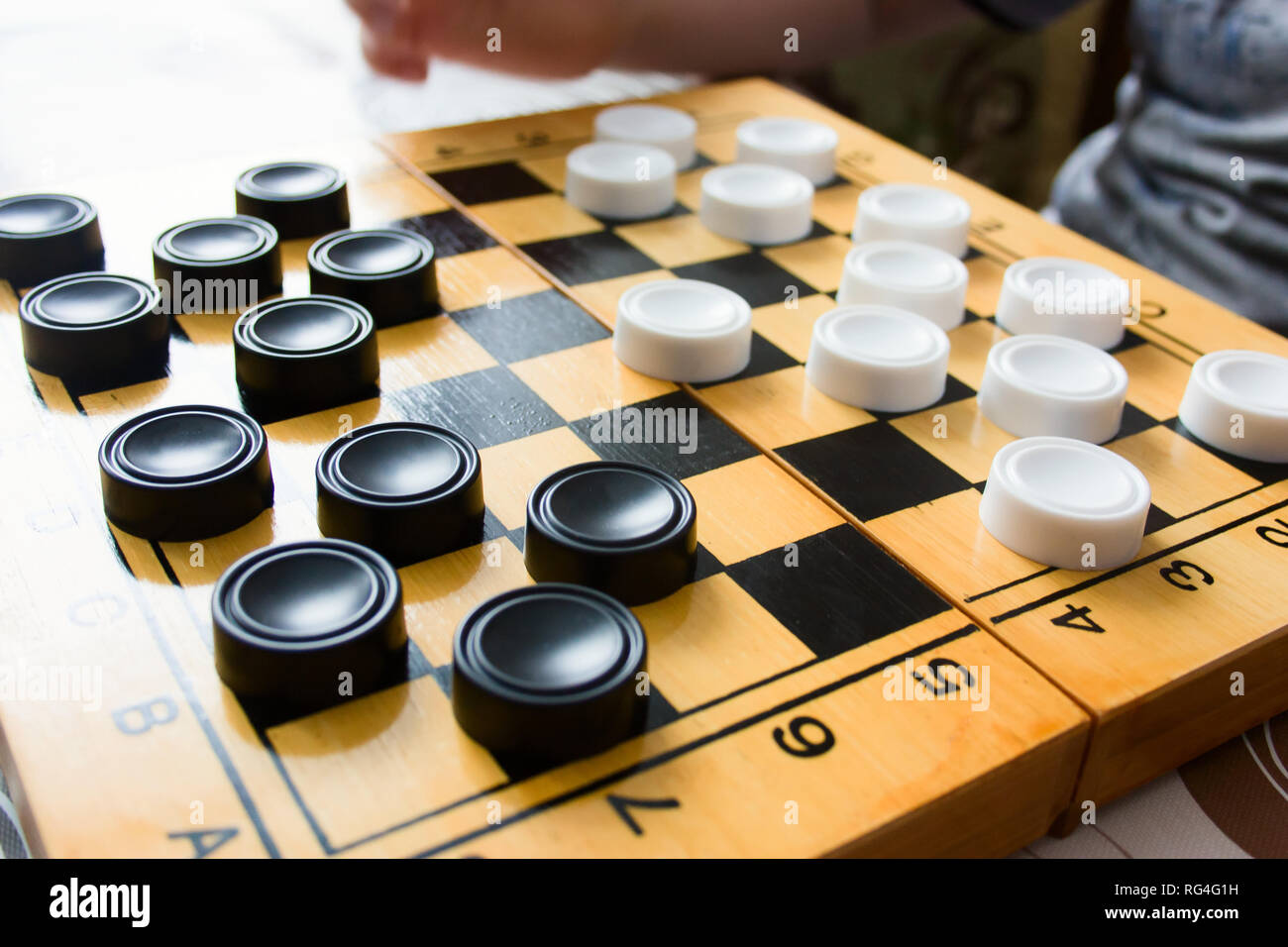 unrecognizable woman and kid playing checkers at home, closeup of a ...