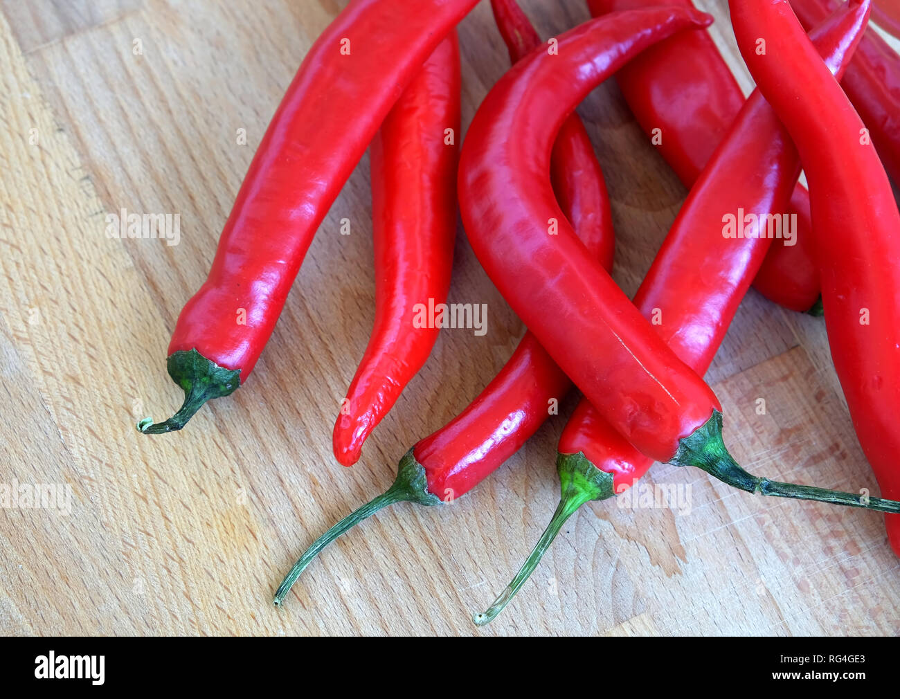 Many red hot chilli peppers on brown wooden surface top view closeup ...