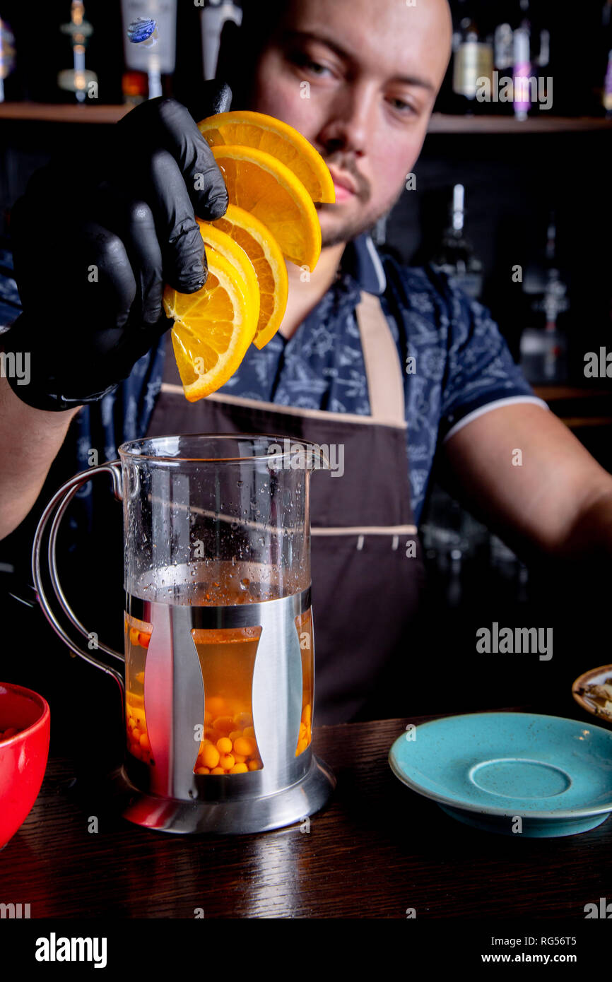 Process brewing tea,tea ceremony. Bartender adds sliced orange into the ...