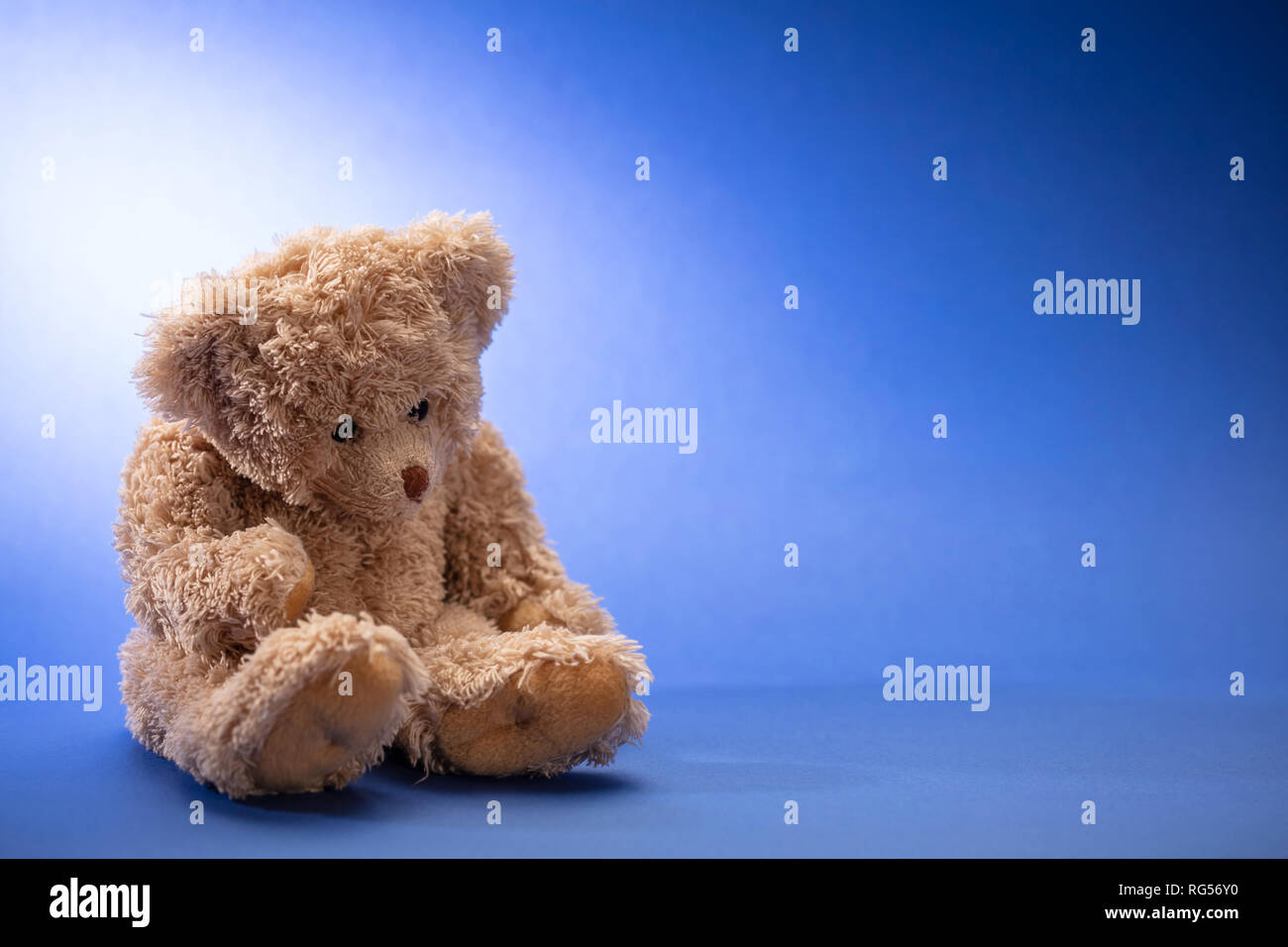 Blue Monday, depression concept. Teddy bear sad, sitting in blue empty ...