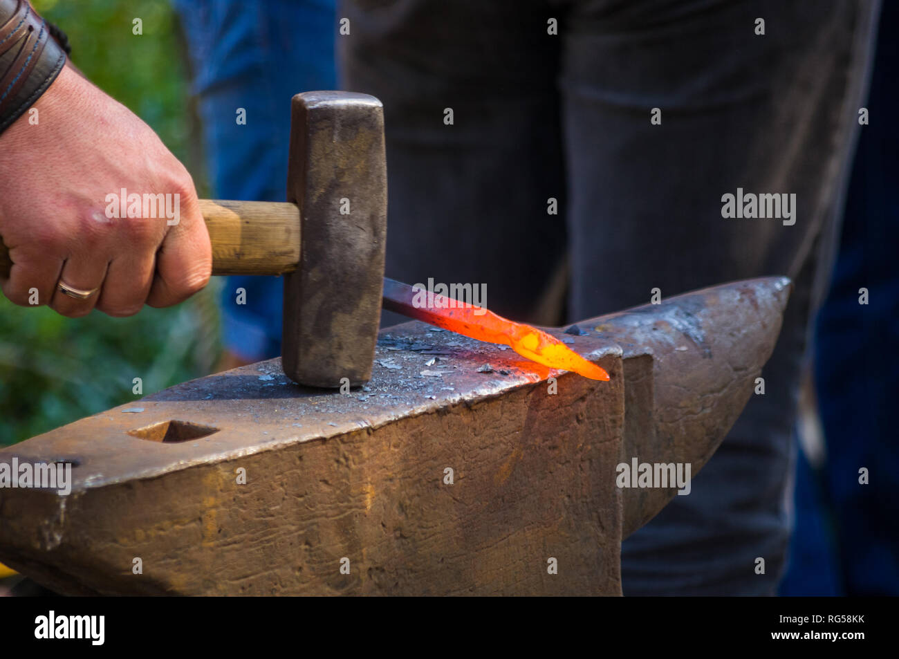 blacksmith performs the forging of hot glowing metal on the anvil ...
