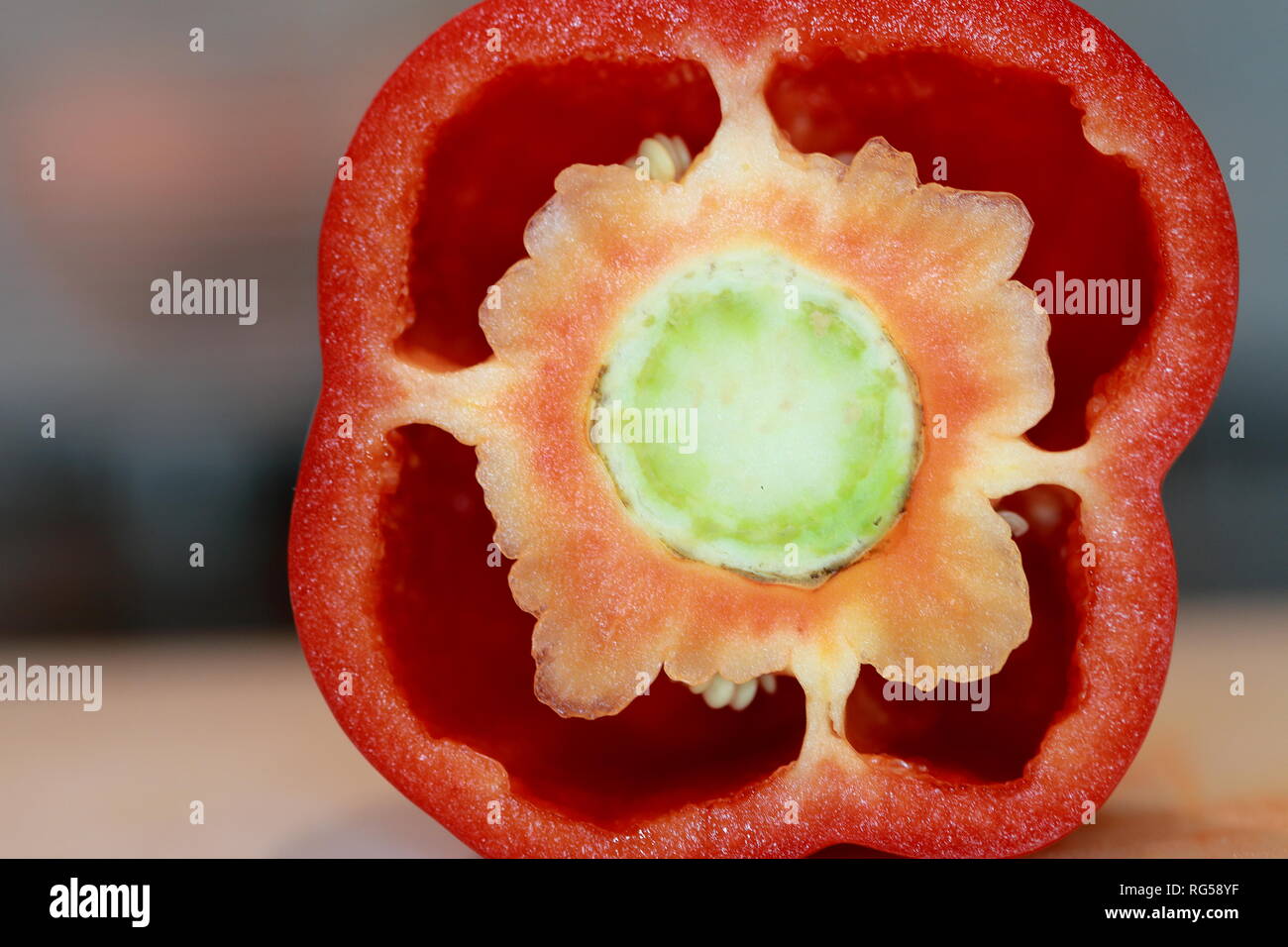 A red bell pepper (capsicum annuum) with its top cm sliced off laid on ...