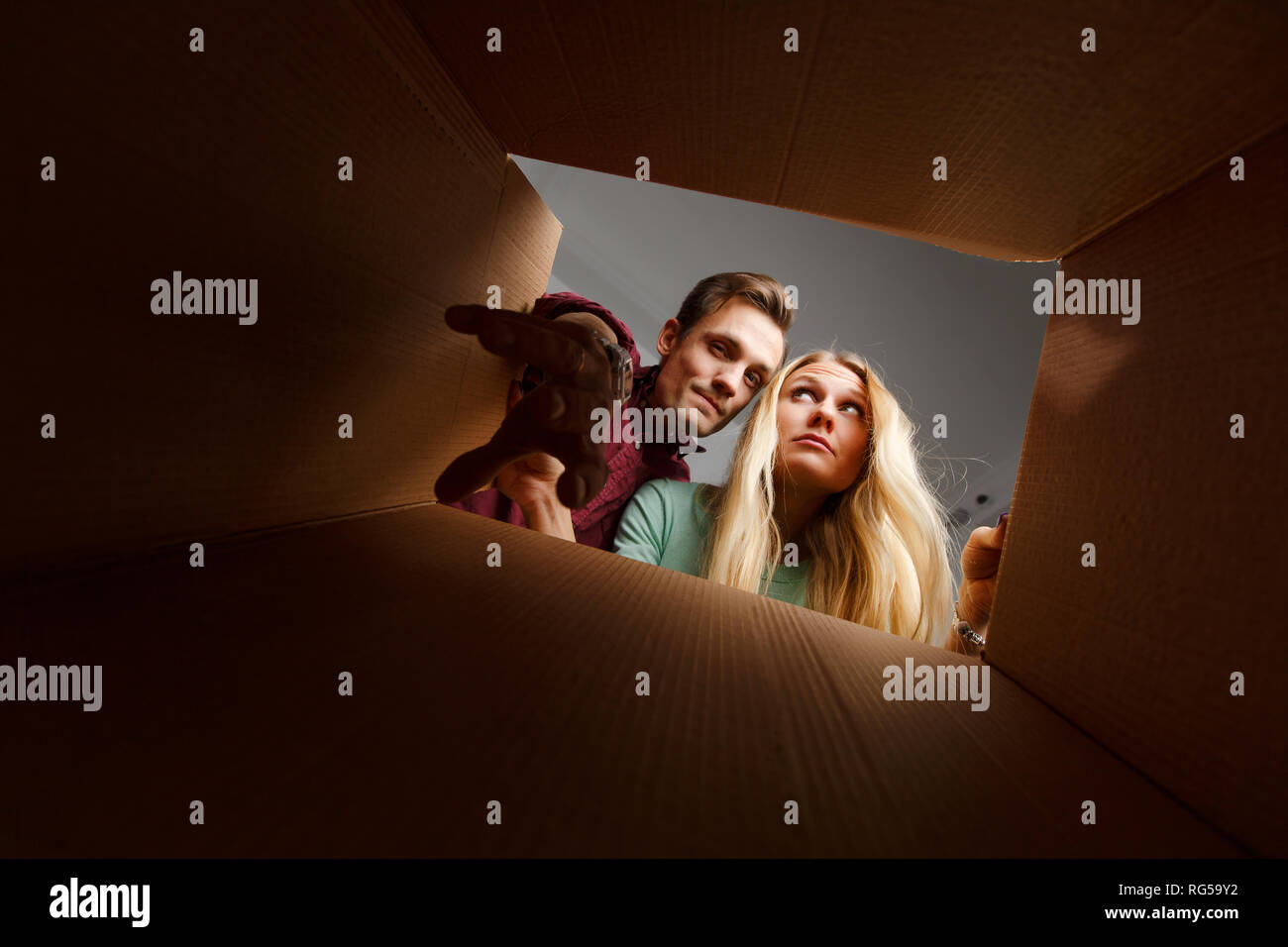 Picture of woman and man looking inside cardboard box Stock Photo - Alamy