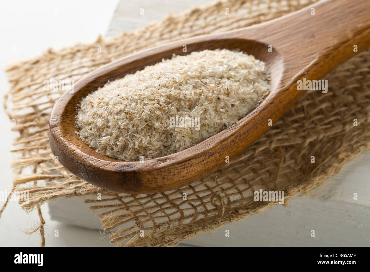 Heap of psyllium husk in wooden spoon on burlap. Psyllium husk also ...