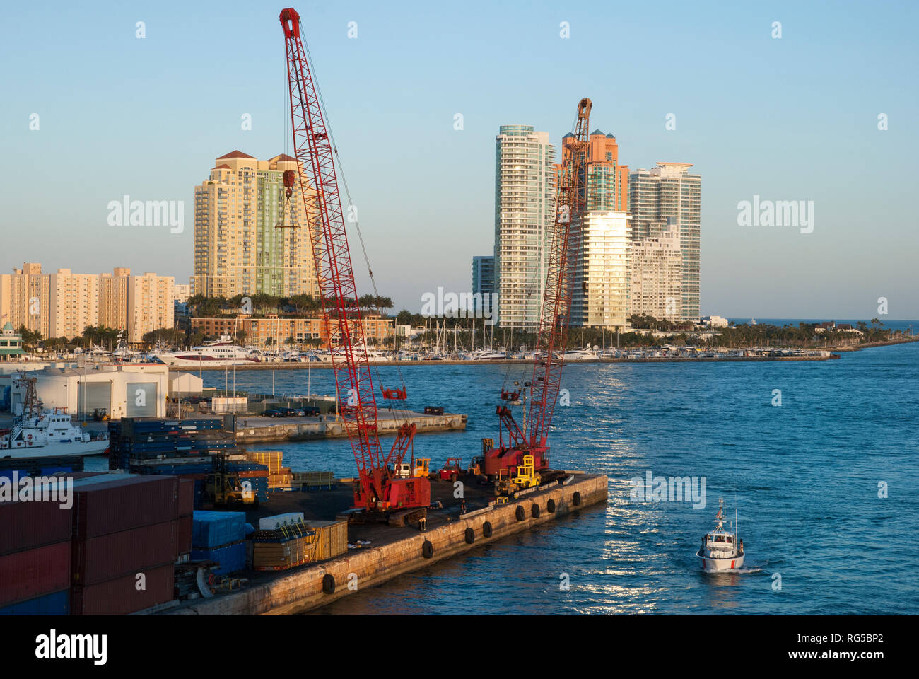 Two port cranes with Miami Beach skyline in a background at dusk ...