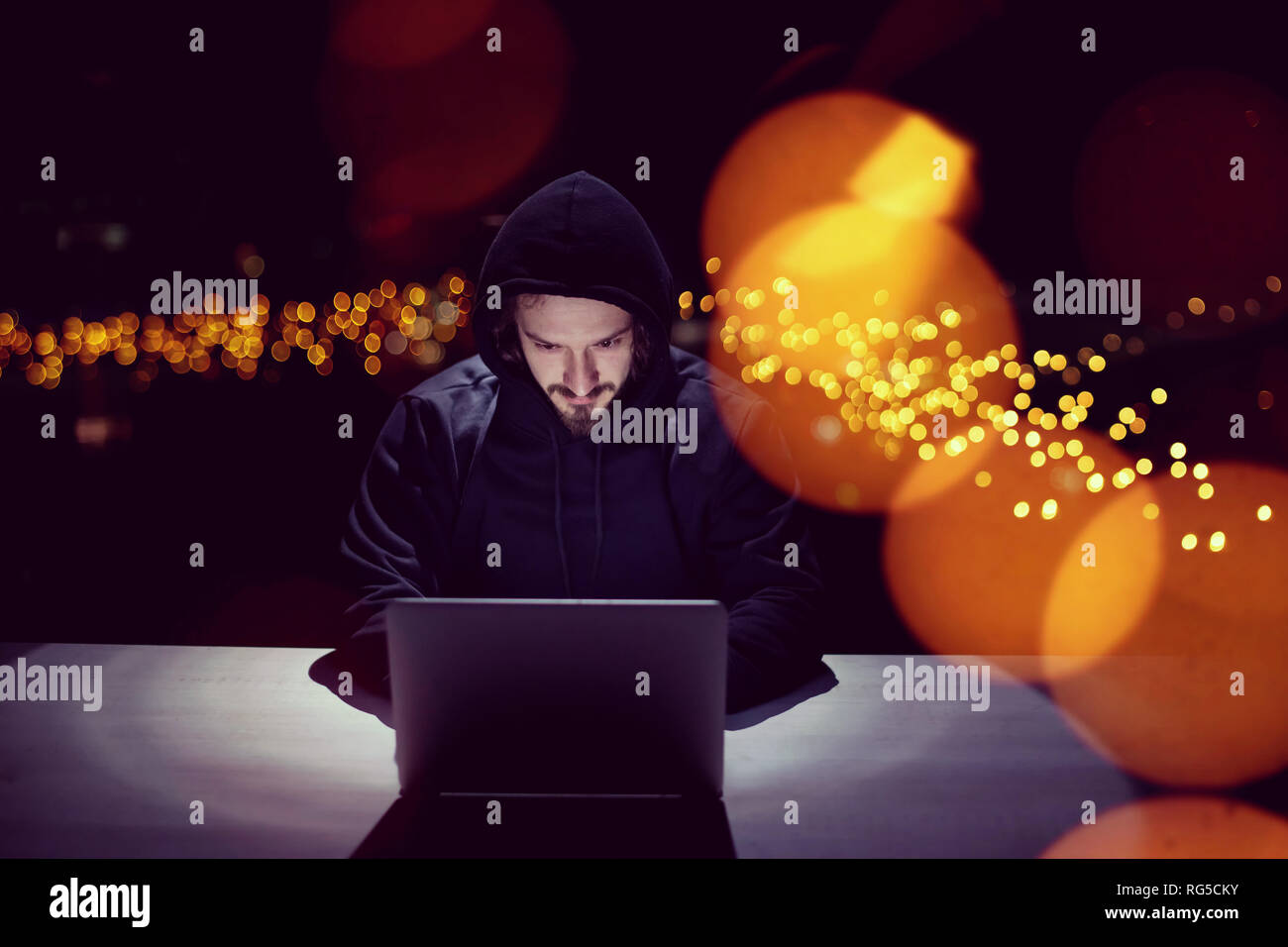 Young talented hacker using laptop computer while working in dark ...