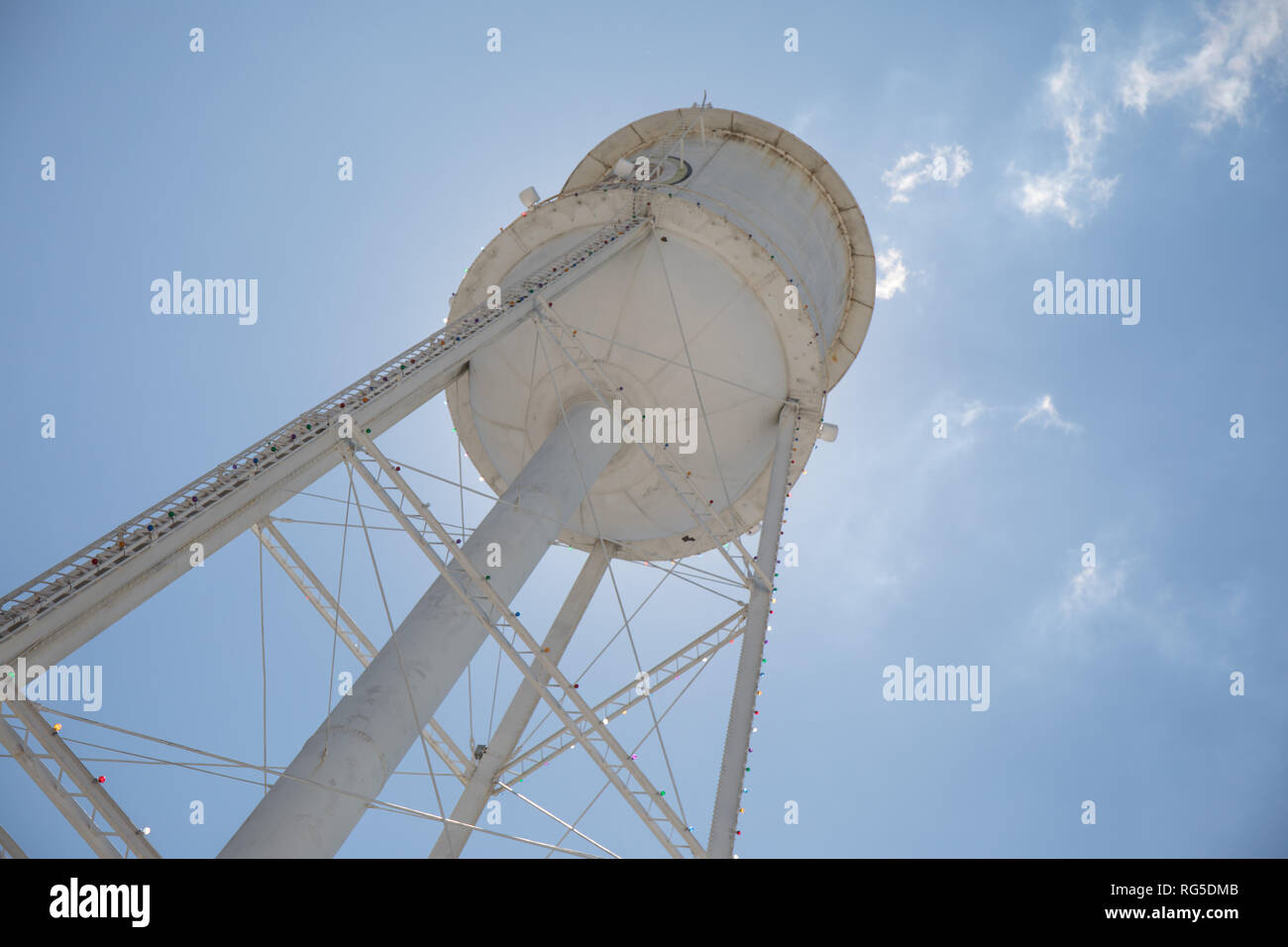 Looking up at a bright white water tower from below backlit with the ...