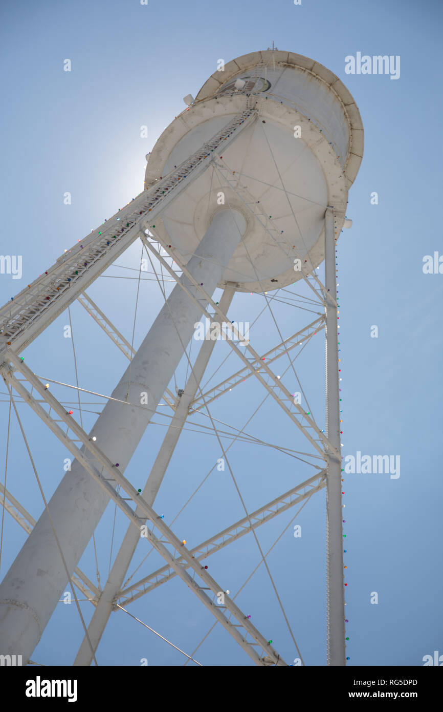 Looking up at a bright white water tower from below backlit with the ...