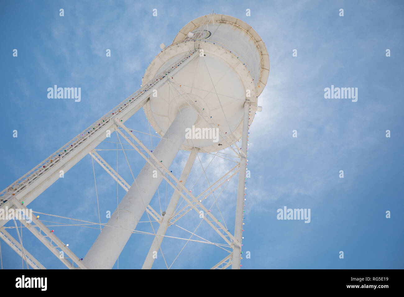 Looking up at a bright white water tower from below backlit with the ...