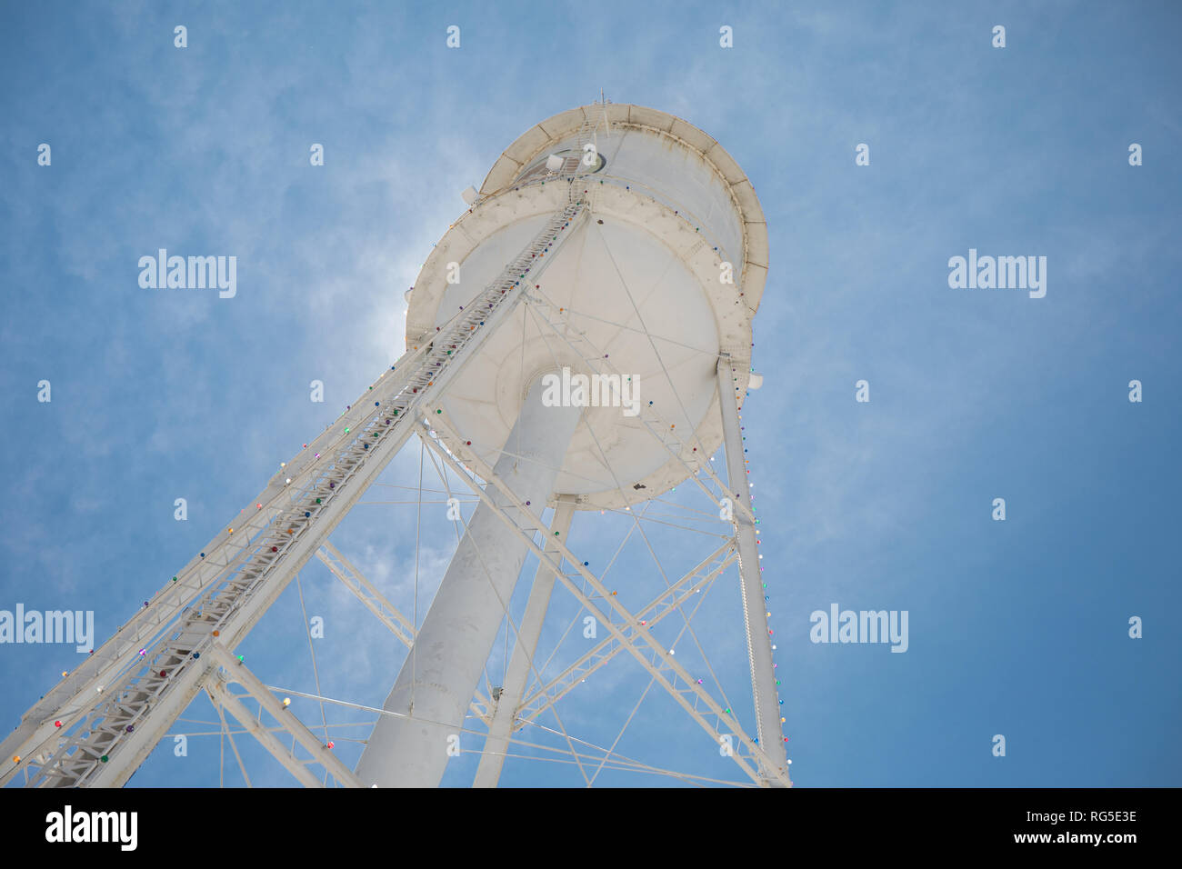 Looking up at a bright white water tower from below backlit with the ...