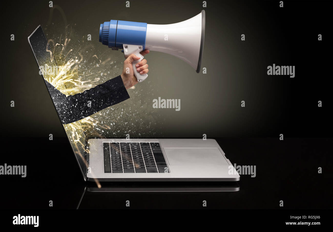 Hand with loudspeaker coming out of a laptop with sparkling effects ...