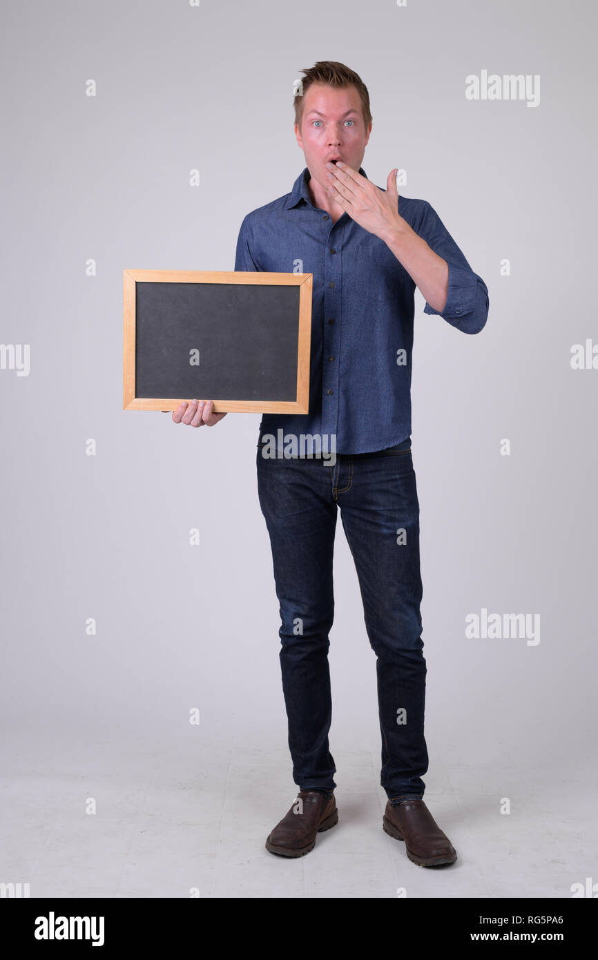 Full body shot of young businessman holding blackboard and looking ...