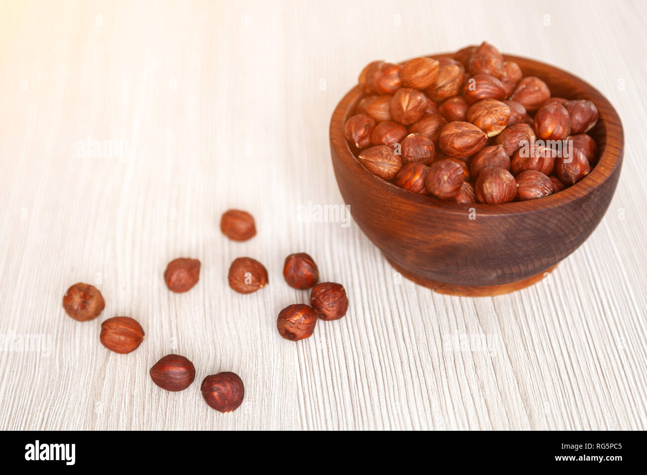 Peeled hazelnut in a cedar pine plate on a wooden isolated background ...