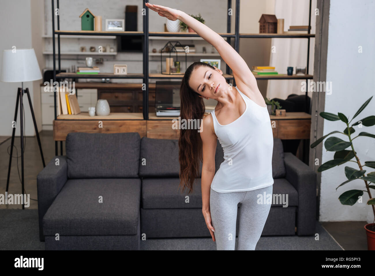 beautiful young woman doing stretching exercise at home in living room ...