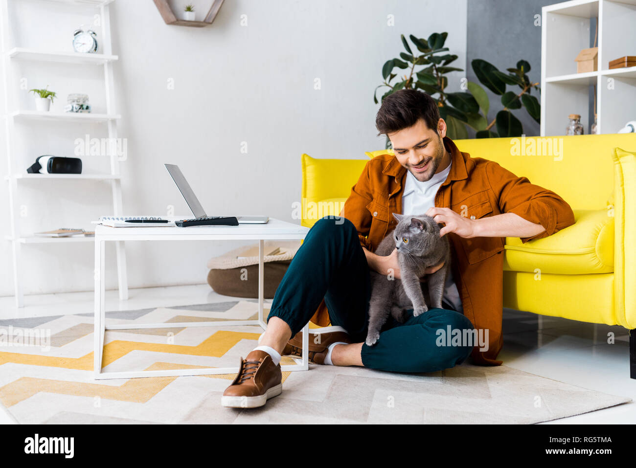 handsome smiling man sitting on floor with british shorthair cat Stock ...