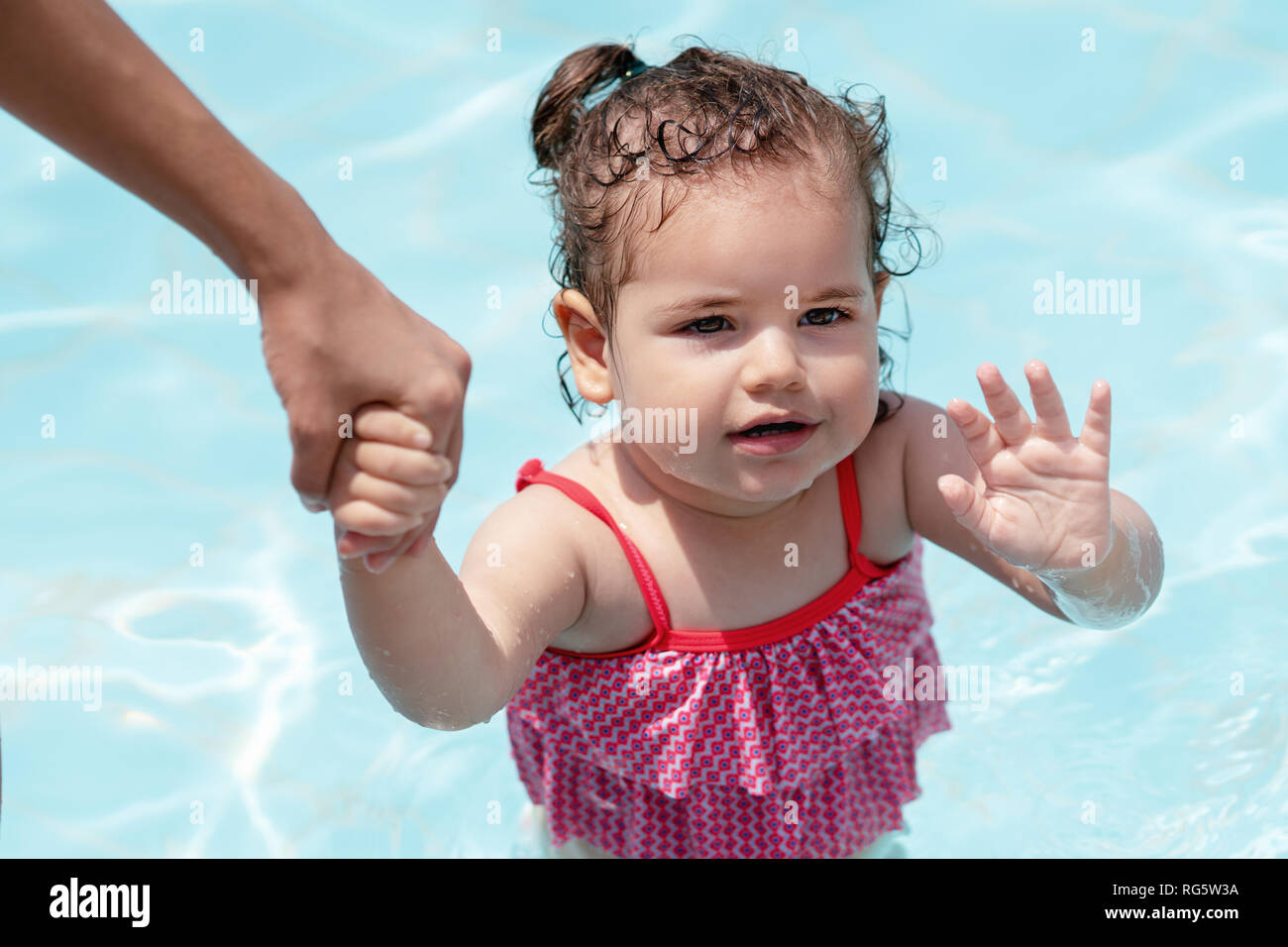 Little child girl swimming and playing in a open pool with happy smile ...