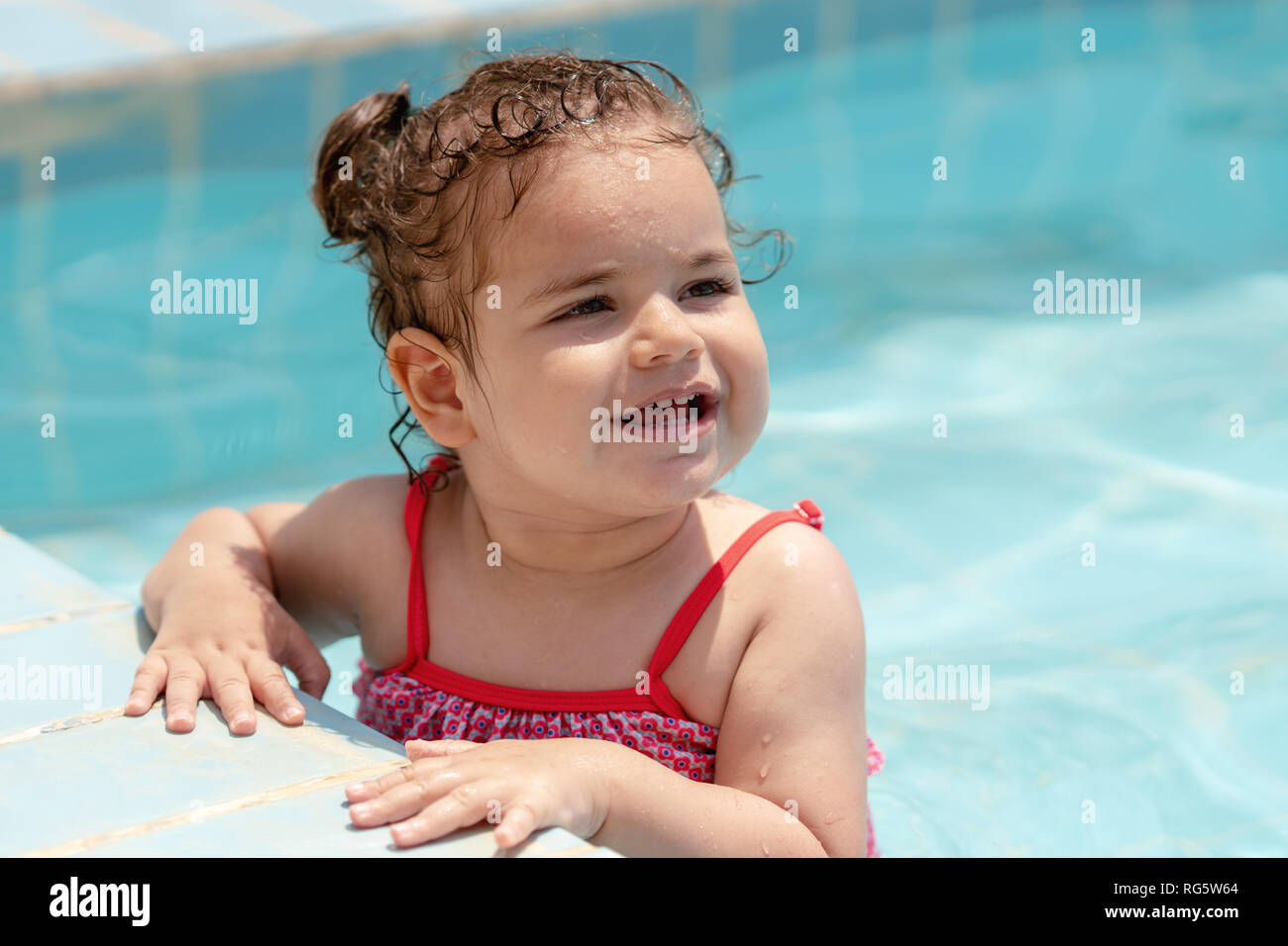 Little child girl swimming and playing in a open pool with happy smile ...
