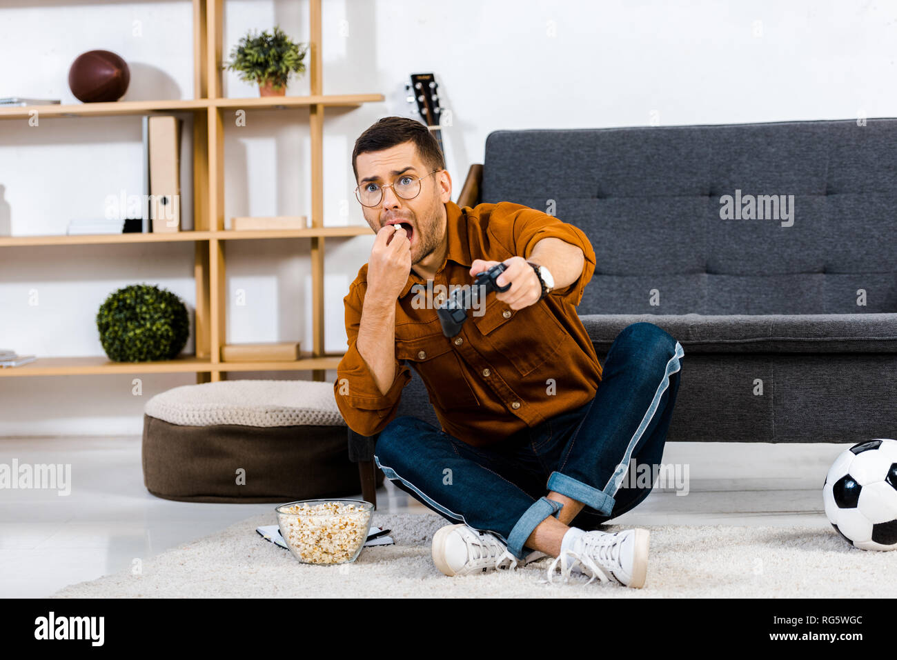 emotional man eating popcorn while playing video game Stock Photo - Alamy