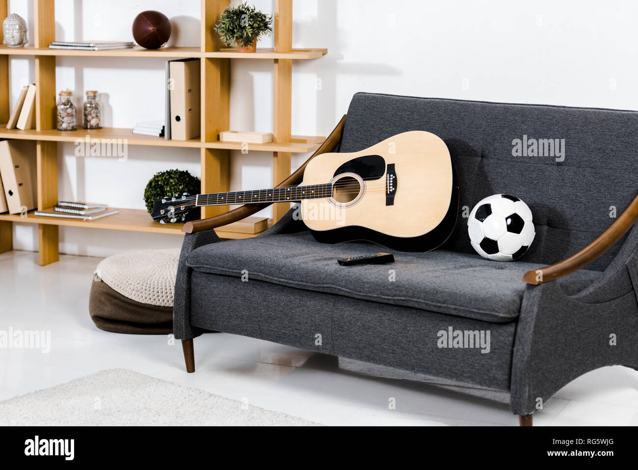 modern living room with acoustic guitar, ball and remote control on ...