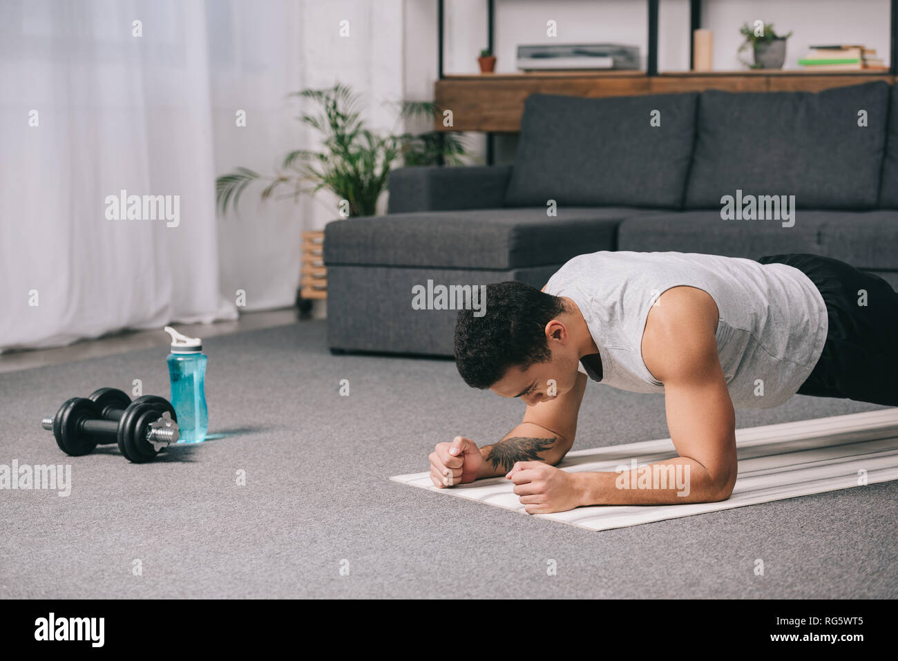 bi-racial man doing plank exercise on fitness mat in apartment Stock ...
